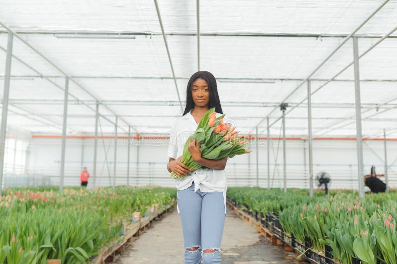 Hermosa Joven Sonriente Trabajadora Afroamericana Con Flores En ... Hermosa Joven Sonriente Trabajadora Afroamericana Con Flores En ...