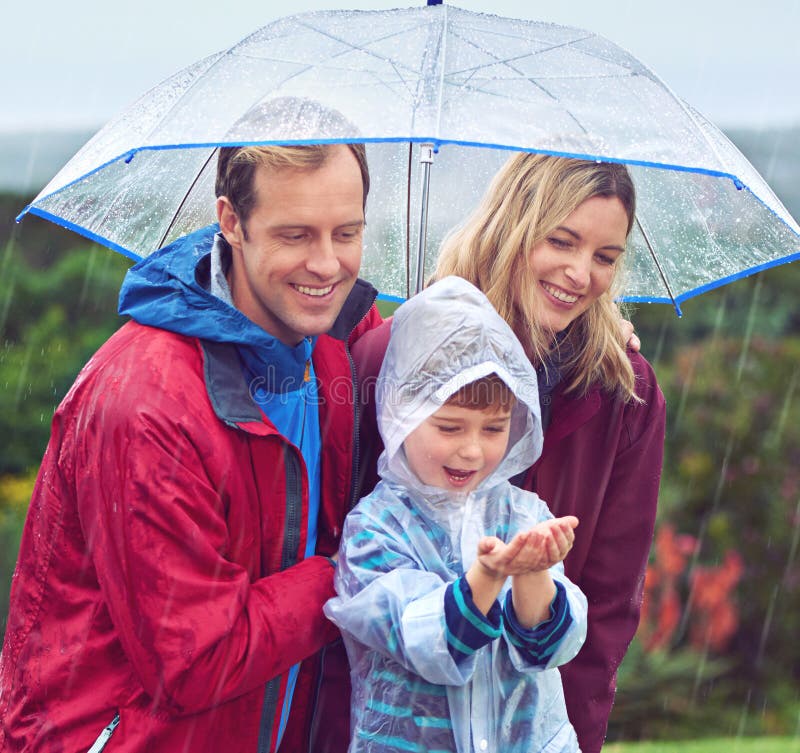 Hes Fascinated by the Rain. a Family of Three Standing Outside in the ...