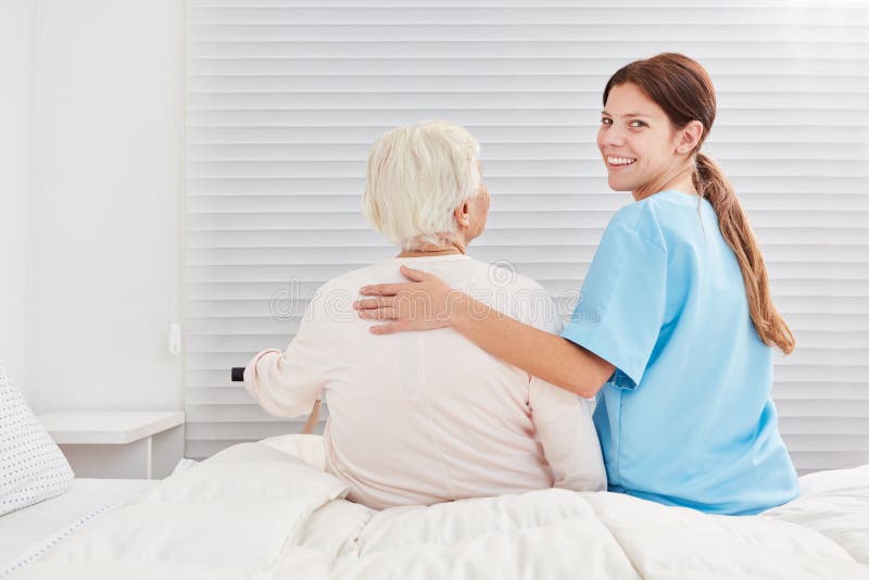 Het Geven De Zorghulp Helpt Bejaarde Uit Bed Stock Afbeelding