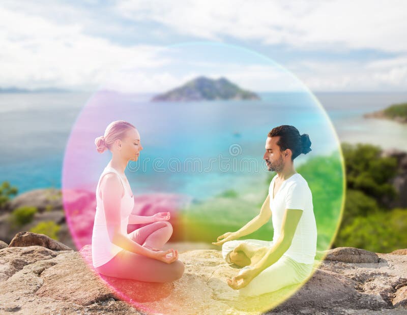 Het Paar Die Yoga In Lotusbloem Doen Stelt Met Regenboogaura Stock