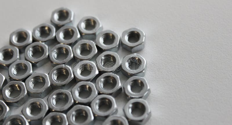 Hex Nuts on a Flat Surface are Huddled Together on the Left Side of the ...