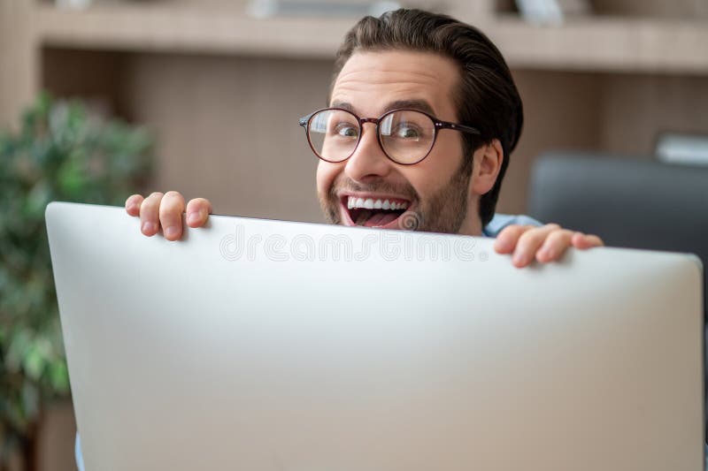 A Dark-haired Man Hiding Behind the Computer and Smiling Stock Image ...