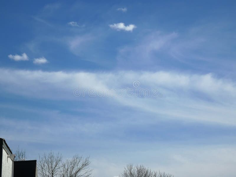 Wispy High Altitude Clouds with a Blue Sky and Trees Stock Photo ...