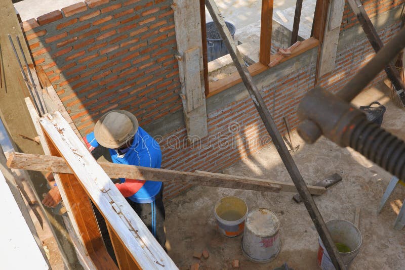Asian Builder is Working To Build Brick Wall Inside of Incomplete House ...