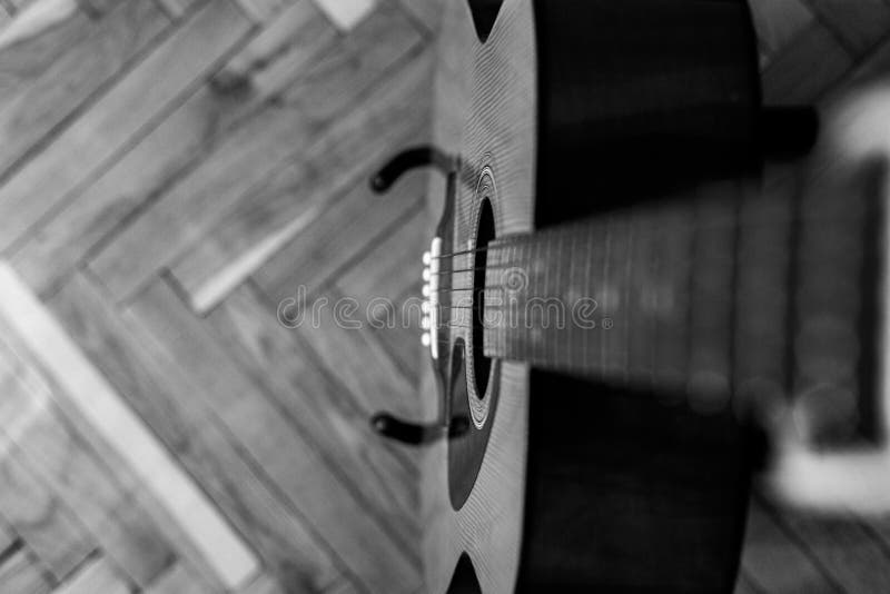 High Angle Greyscale of an Acoustic Guitar on a Stand on the Floor ...