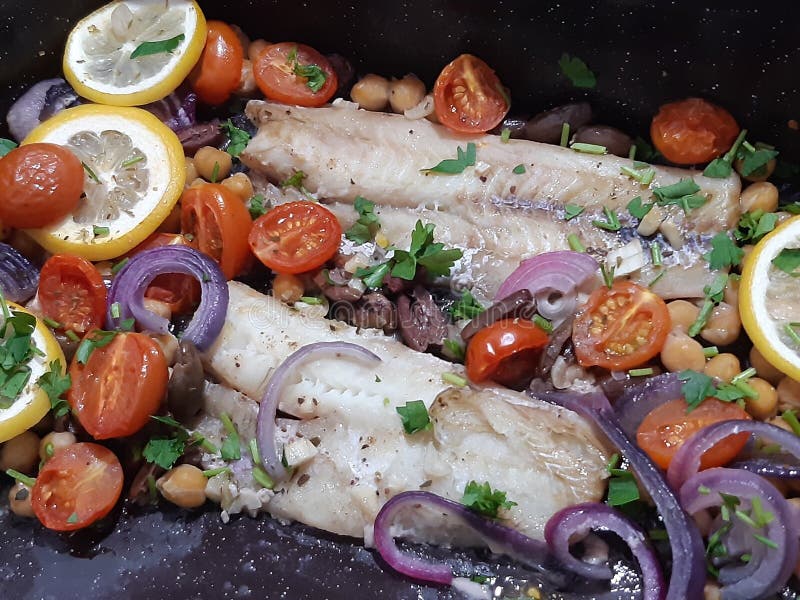 High Angle Shot Of Cooked Fish With Lemons Tomatoes And Onions Stock ...