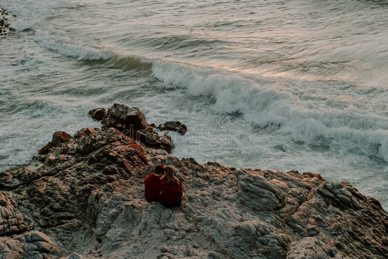 High Angle Shot of a Couple Sitting on Cliffs Near the Sea Stock Image ...