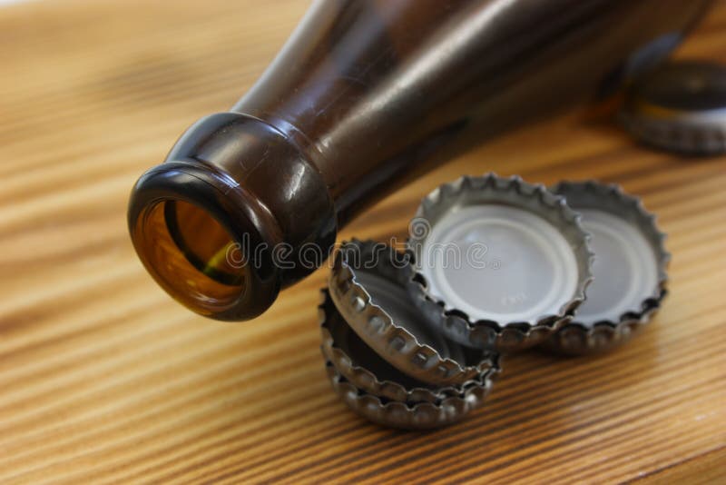 High-angle Shot of an Empty Beer Bottle with Bottle Caps on a Wooden ...