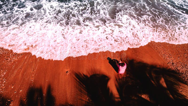 High Angle Shot of a Person Sitting on the Red Sand at the Beach Stock ...