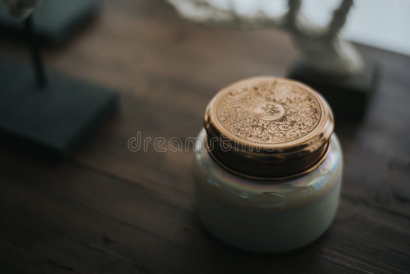 High Angle Shot of a White Container with a Golden Lid on a Dark Wooden ...