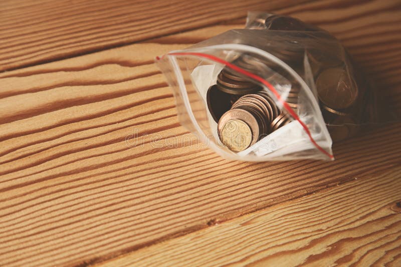High Angle Shot of a Zip Log Full of Coins on a Wooden Surface Stock ...