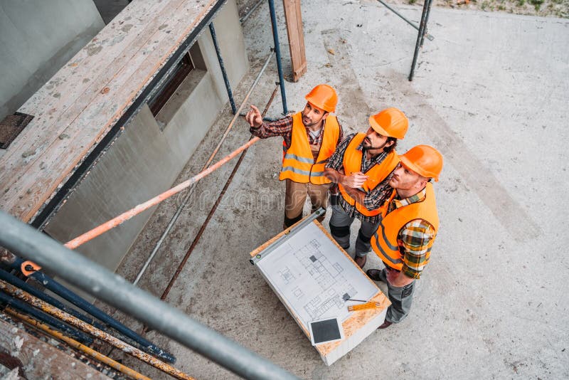High Angle View of Group of Builders Discussing Building Plan at ...
