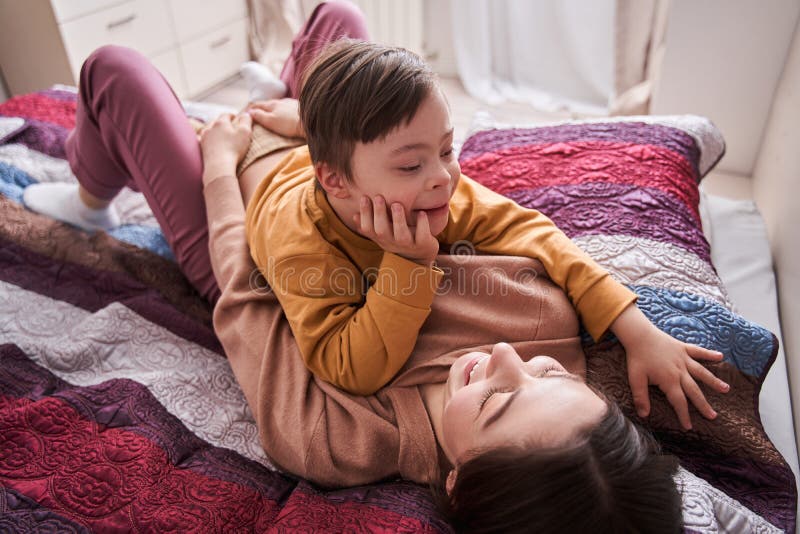Mom Enjoying Time With Her Son While Laying At The Bed And Looking At