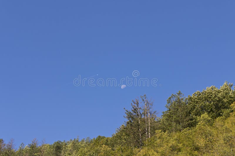 High Flying Plane and the Moon in the Blue Sky. Selective Focus Stock ...