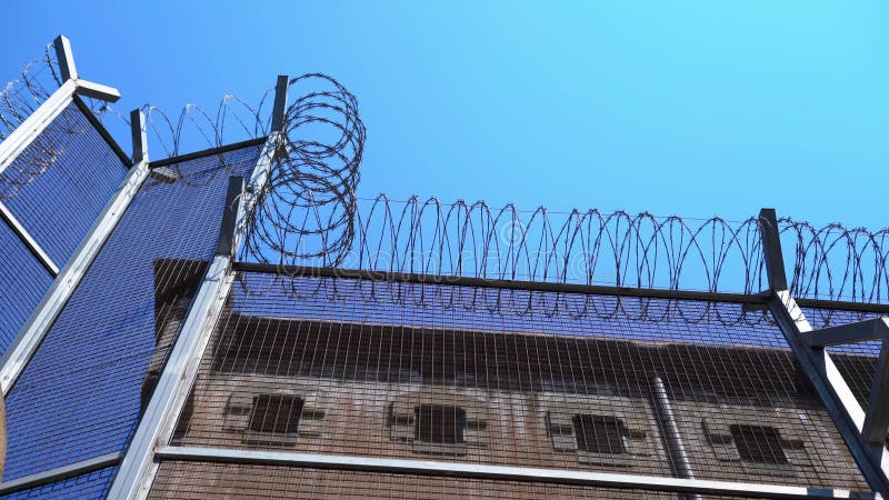 High Prison Fence with Barbed Wire Against a Clear Sky. Bottom View ...