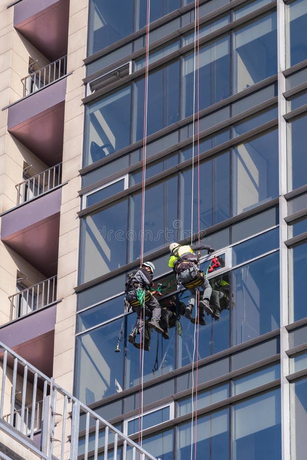High-rise Workers with Climbing Equipment Change the Window in the High ...