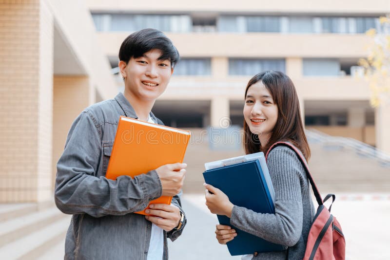High School Students Hold Book and Laptop Talking and Laughing in a ...