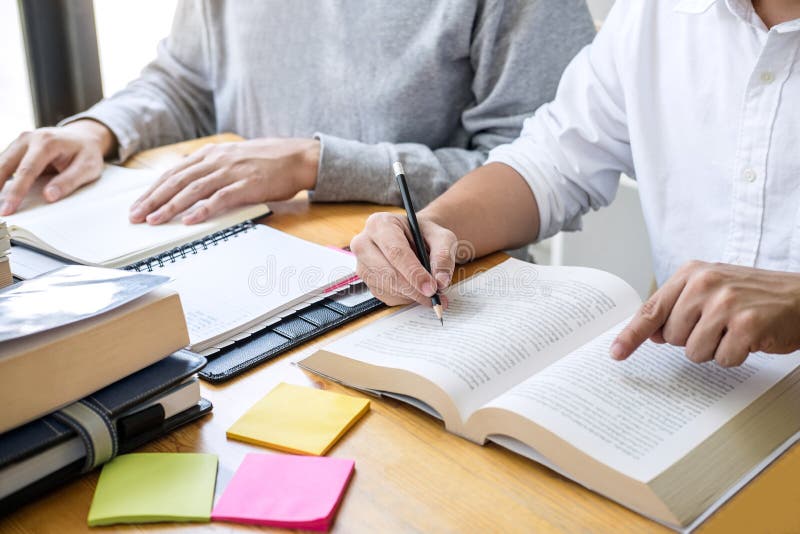 High School Tutor or College Student Group Sitting at Desk in Library ...