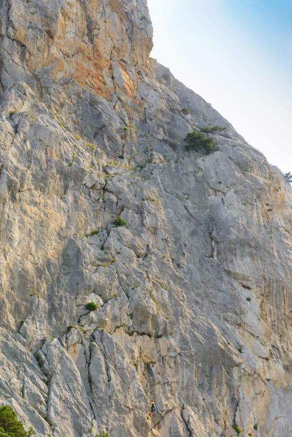 High Steep Cliff with a Small Rock Climber at the Bottom Stock Photo ...