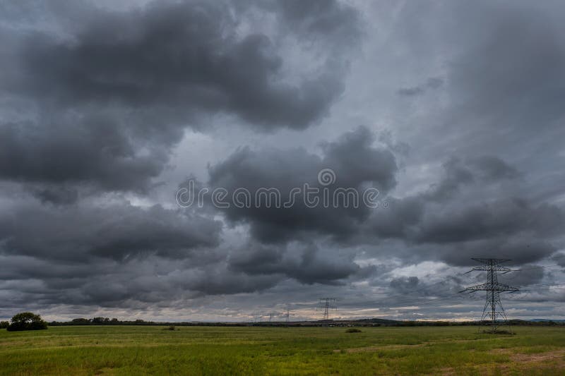 High Voltage Overhead Power Line. Green Meadow with a Cloudy Stormy Sky ...