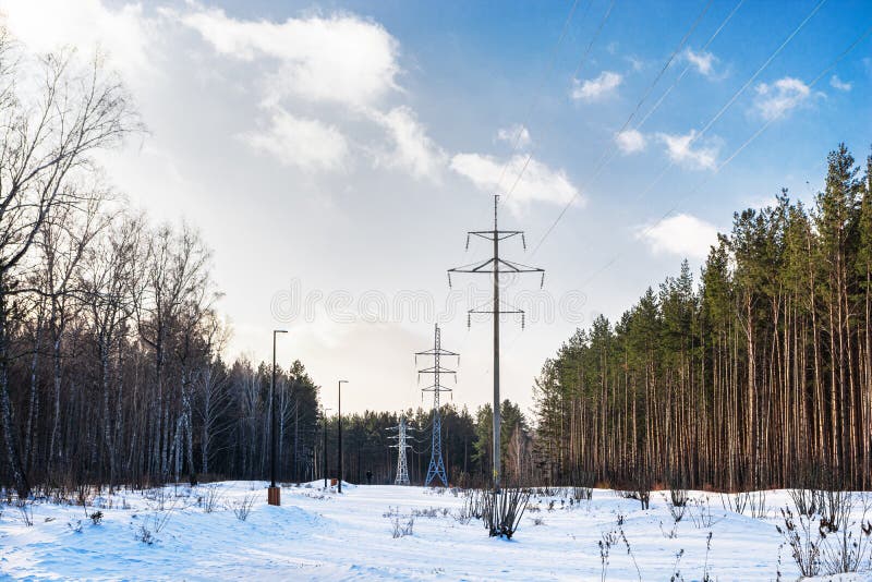 A High-voltage Power Line Stands in the Forest in Winter Under a Blue ...
