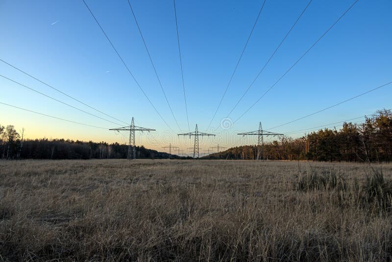 High Voltage Power Lines Over a Field at Sunset Stock Photo - Image of ...