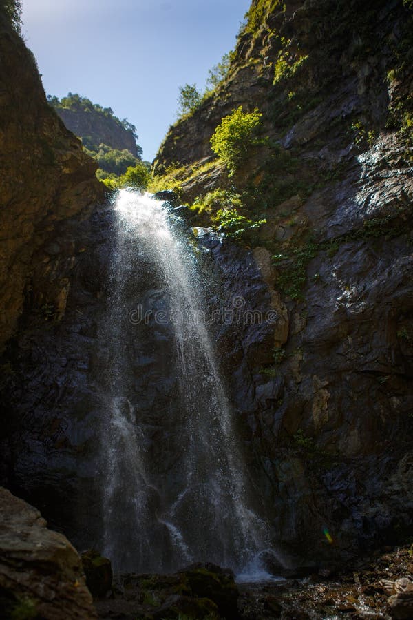 A High Waterfall with White Splashes of Water Descends from the ...