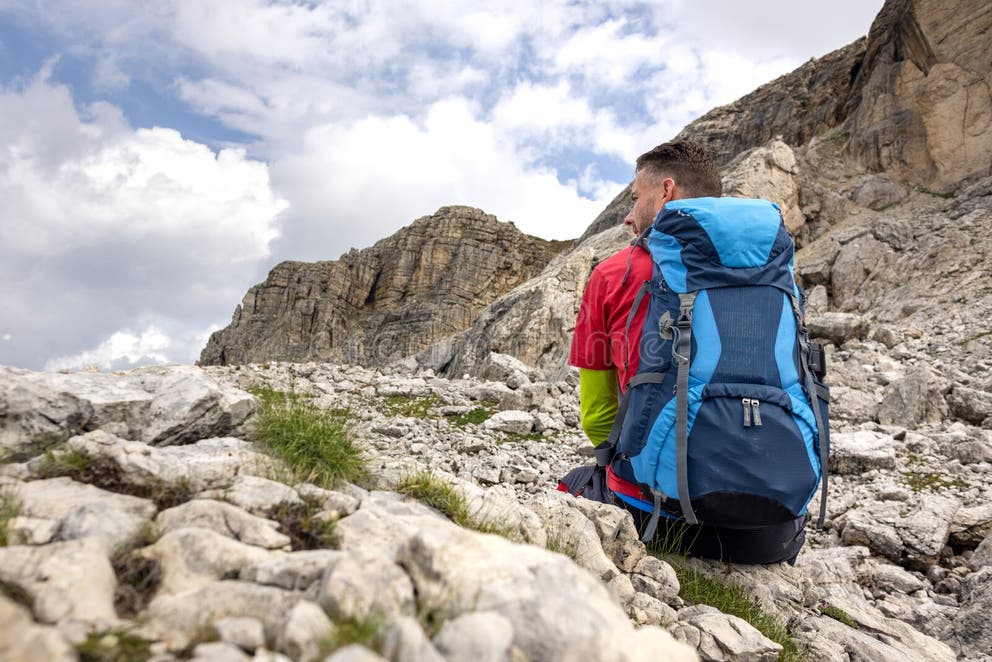 Hiker with a Large Backpack Sitting on Rocks on a Mountainside Stock ...