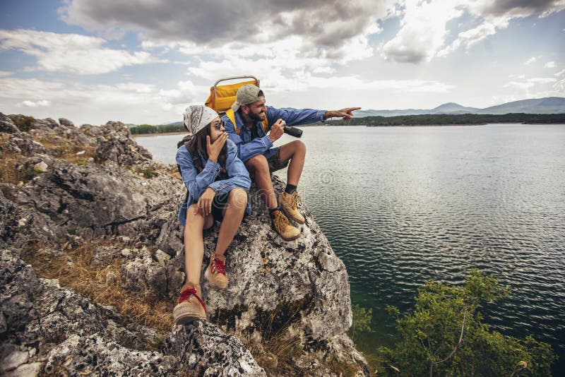 Hikers with Backpacks Sitting on Cliff Enjoying at the Mountain Lake ...