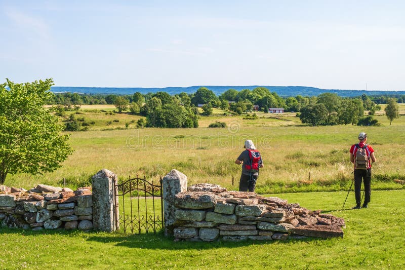 Hikers by an Old Iron Gate by a Stone Wall Looking at the Rural ...