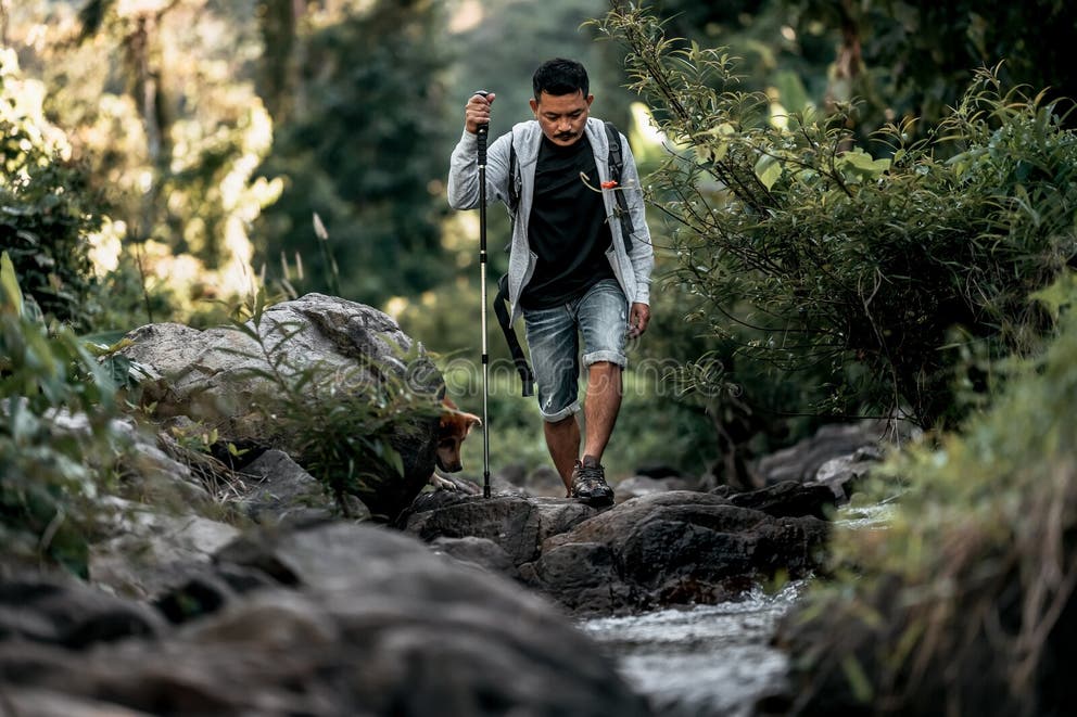Hikers Walk on Rocks in the Stream Flowing from the Waterfall in the ...