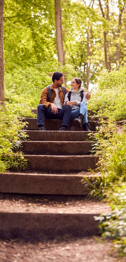 Hiking Couple with Backpacks Sitting on Steps on Path through Trees in ...