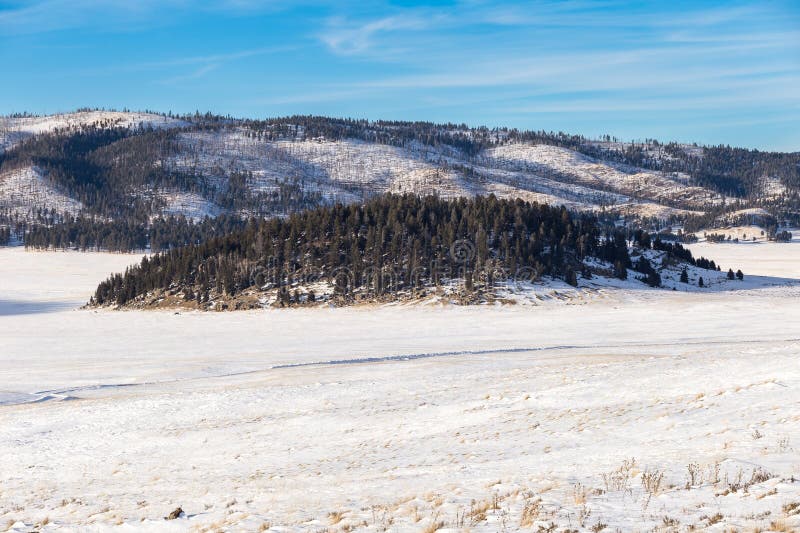 Hill Covered in Trees and Snow in Front of Low Mountain Range Stock ...