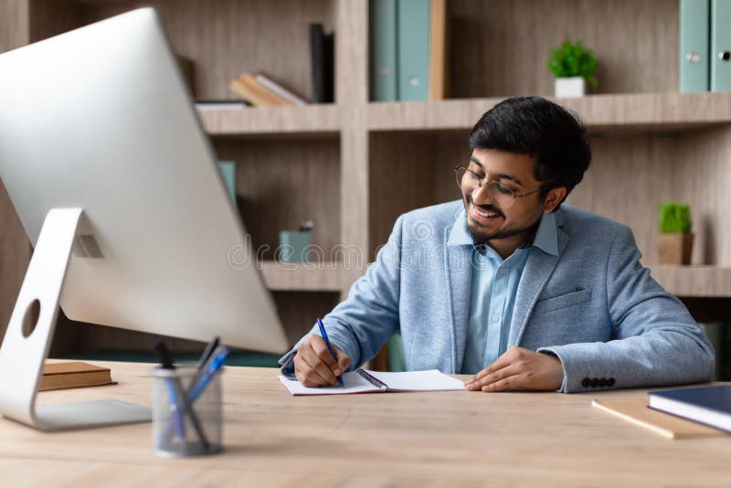 Hindu Businessman Sits at Desktop Computer Taking Notes in Office Stock ...