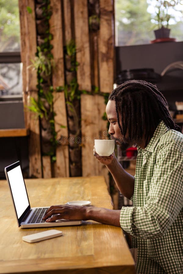 Hipster Drinking a Cup of Coffee while Using a Laptop Stock Image ...