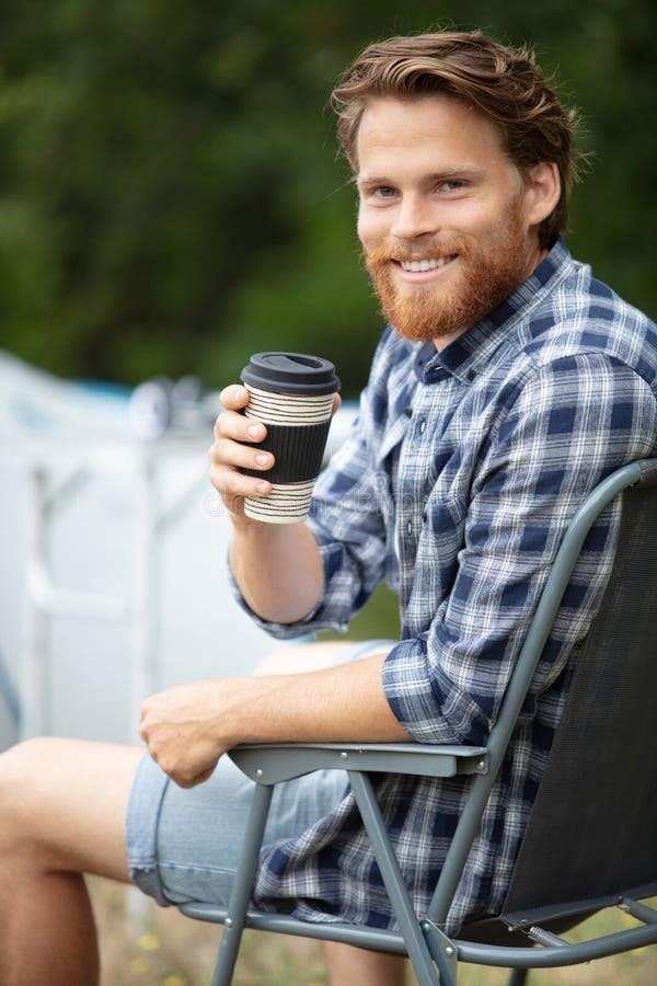 Hipster Man Sits on Folding Chair at Campsite Drinking Coffee Stock ...