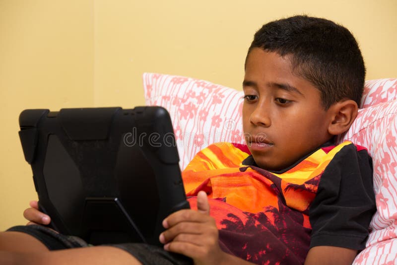 Hispanic Boy Using Tablet while in Bed Stock Photo - Image of ...