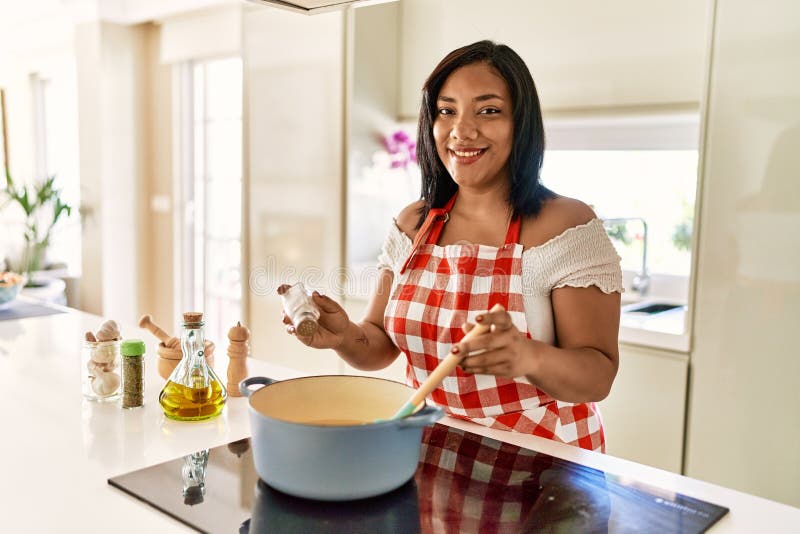 Hispanic Brunette Woman Cooking Adding Salt at the Kitchen Stock Image ...