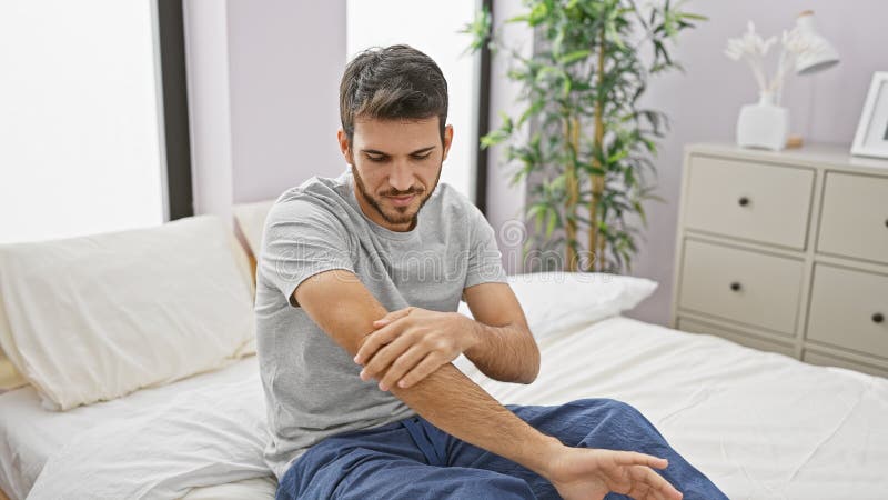 Hispanic Man Applying Lotion on Elbow in a Cozy, Well-lit Bedroom ...