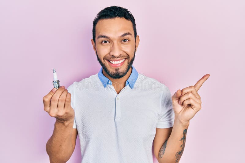 Hispanic Man with Beard Holding Spark Plug Smiling Happy Pointing with ...
