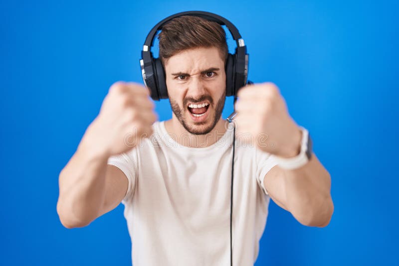 Hispanic Man With Beard Listening To Music Wearing Headphones Angry And