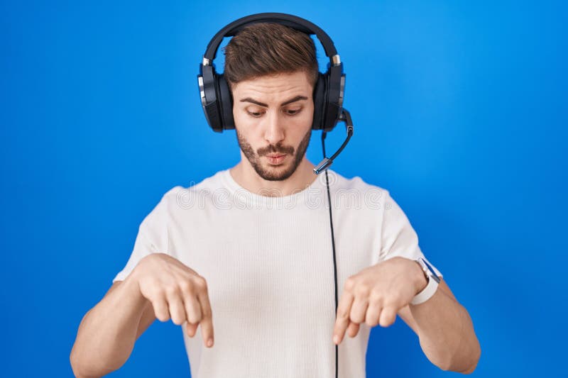 Hispanic Man With Beard Listening To Music Wearing Headphones Pointing