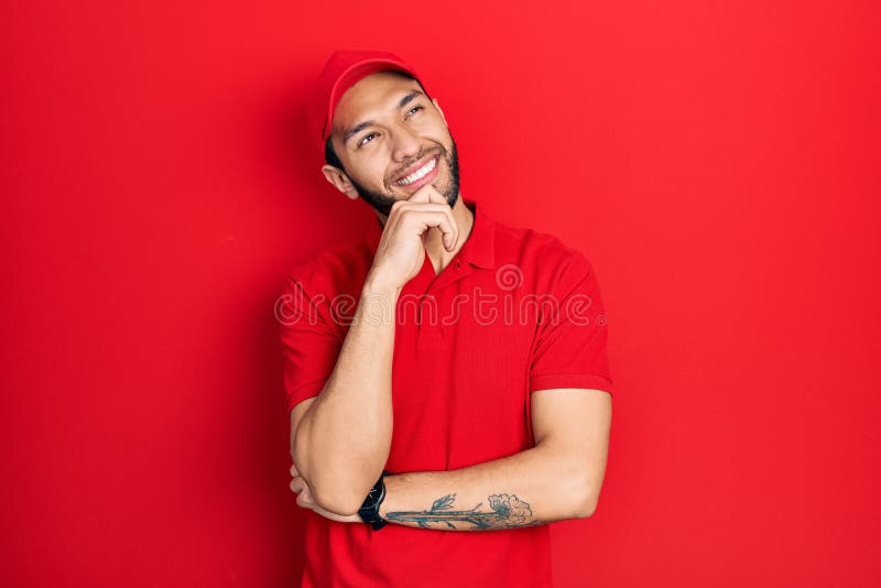 Hispanic Man With Beard Wearing Delivery Uniform And Cap With Hand On