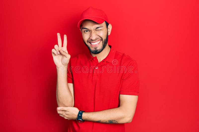 Hispanic Man With Beard Wearing Delivery Uniform And Cap Smiling With