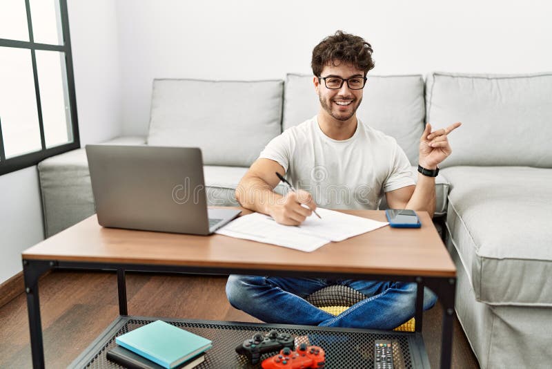 Hispanic Man Doing Papers at Home with a Big Smile on Face, Pointing ...