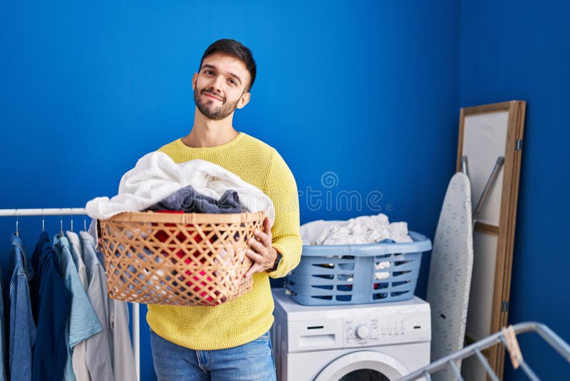 Hispanic Man Holding Laundry Basket Relaxed with Serious Expression on ...