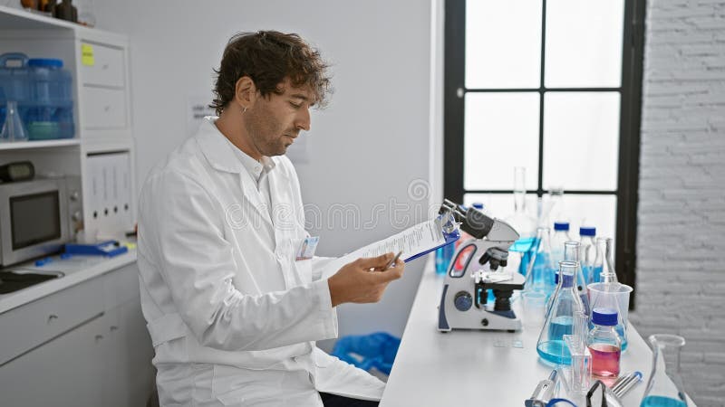 Hispanic Man in Lab Coat Analyzing Notes at a Modern Laboratory ...