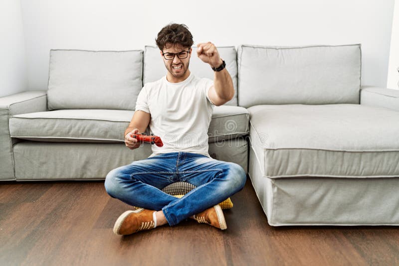 Hispanic Man Playing Video Game Holding Controller by the Sofa Annoyed ...