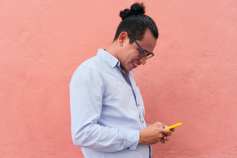 Hispanic Man Standing Checking Cell Phone in Front of Pink Wall Stock ...