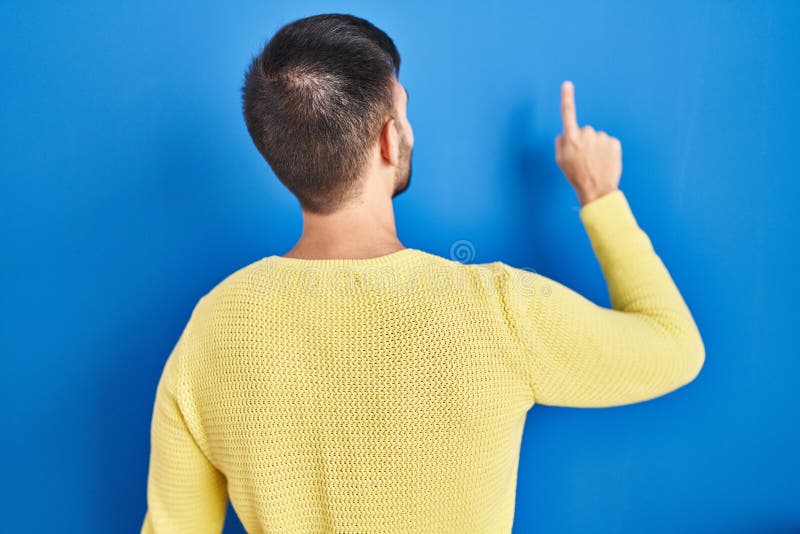 Hispanic Man Standing Over Blue Background Posing Backwards Pointing ...